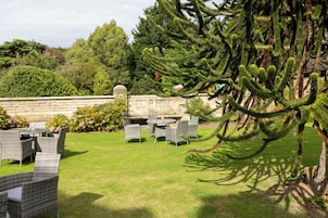 Um jardim com muro de pedra, gramado e móveis de exterior.