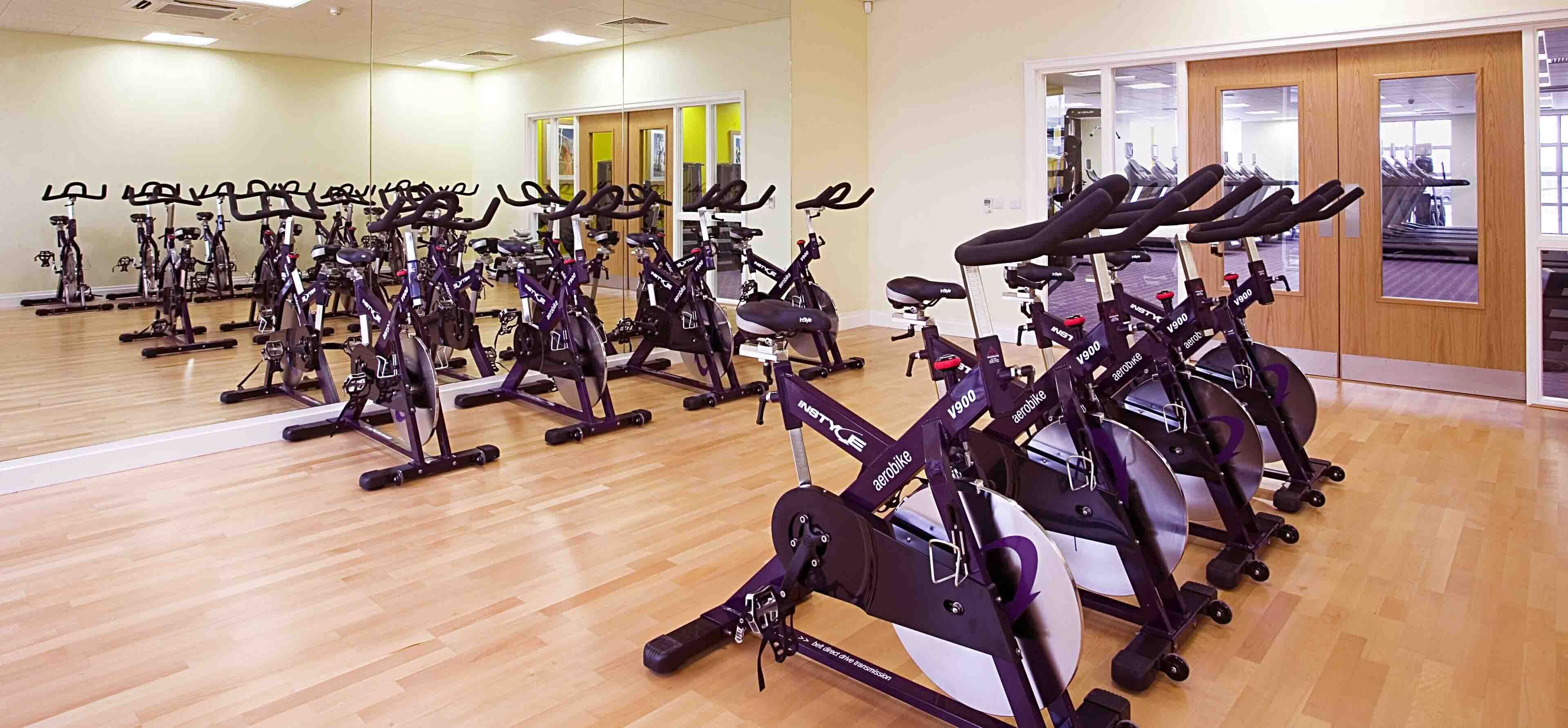 Uma academia com várias bicicletas ergométricas dispostas em fileiras.