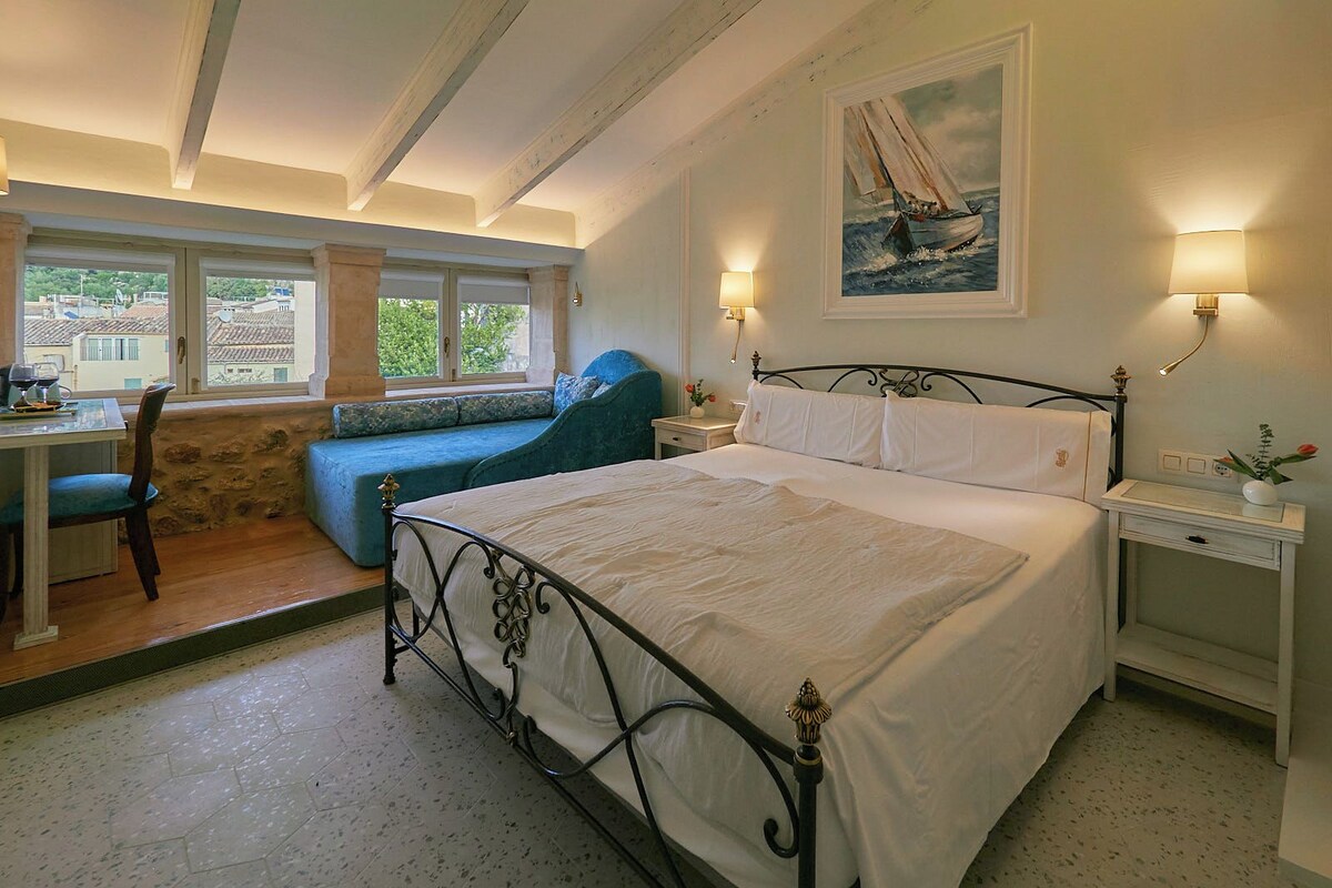 Quarto com cama, escrivaninha, cadeira, janela e um quadro.