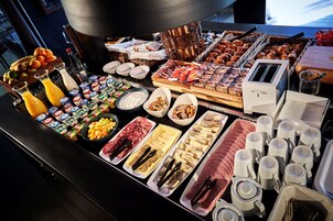 Um buffet com diversos itens de comida, incluindo frutas, queijos, carnes e doces.