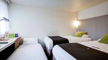 Quarto de hotel com duas camas de solteiro, uma escrivaninha com abajur e mesa de cabeceira.