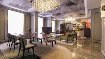 Um hall de hotel moderno com uma grande mesa de jantar, assentos confortáveis, um espaço de bar e um design de teto único.