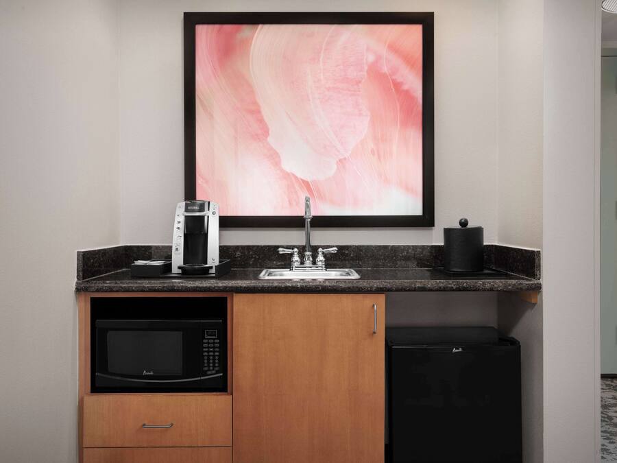 Cozinha compacta com micro-ondas, cafeteira e pia.