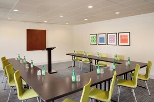 Uma sala de conferências com uma mesa comprida, cadeiras amarelas e obras de arte emolduradas na parede.