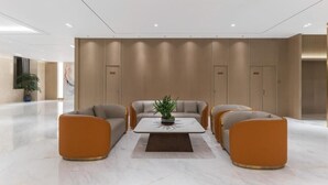 Um lobby moderno com uma mesa de centro, dois sofás e um vaso de planta.