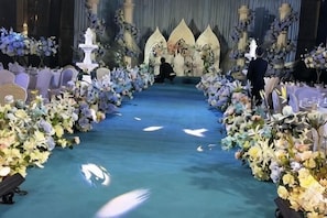 Um corredor cerimonial com arranjos florais e um altar central.