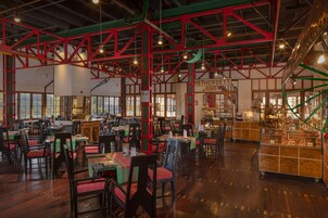 Um restaurante espaçoso com pé direito alto, vigas aparentes e diferentes opções de assentos.