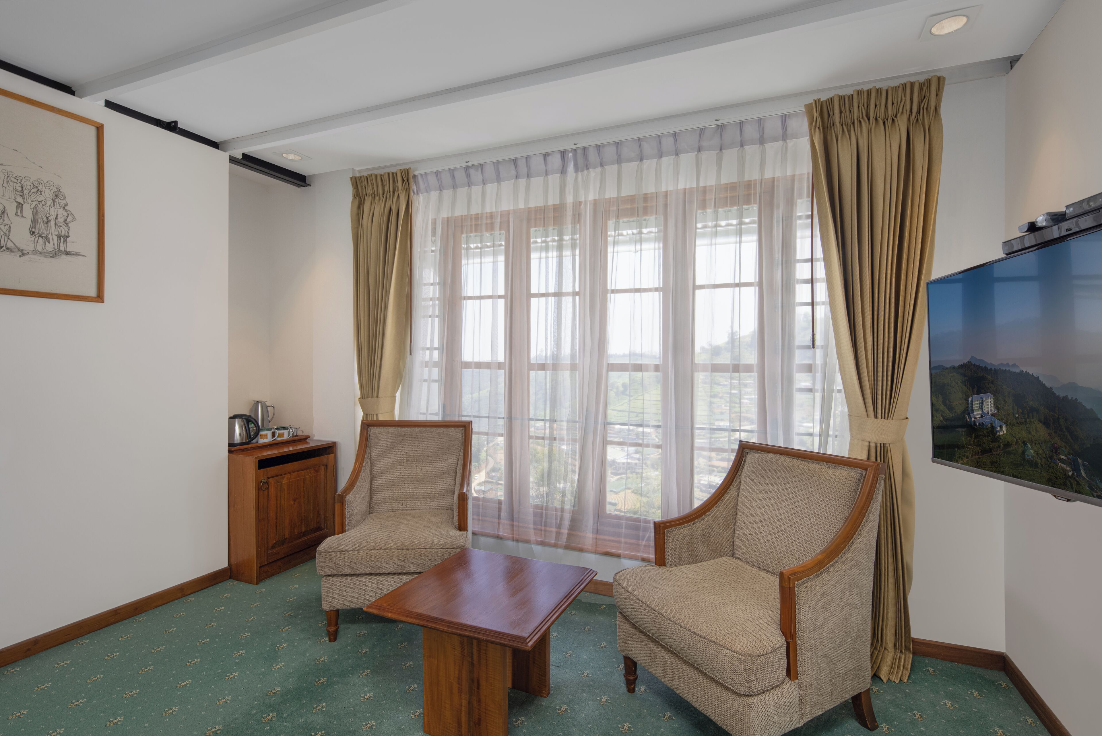 Quarto com duas poltronas, uma mesa de centro de madeira, um armário e uma televisão na parede.