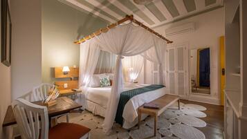 Quarto com cama de dossel, mesa de cabeceira com abajur, cadeira e tapete redondo de fibra.