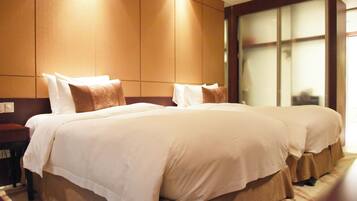 Quarto de hotel com duas camas, um espelho grande e uma porta de correr.