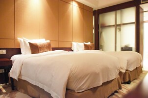 Quarto de hotel com duas camas, um espelho grande e uma porta de correr.