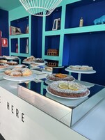 Exposição de sobremesas em um ambiente com paredes verde-água e design moderno.