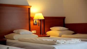 Quarto de hotel com cabeceira de madeira, luminária ao lado da cama e camas bem arrumadas com lençóis brancos.