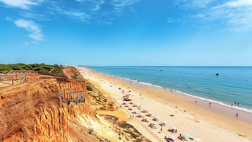Perto da praia, praia de areia branca, guarda-sóis de praia