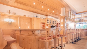 Uma área de bar com balcões de madeira, banquetes e prateleiras com garrafas.