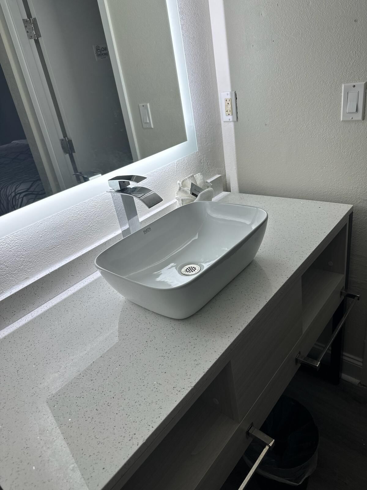 Casa de banho com lavatório branco, espelho e porta-toalhas.