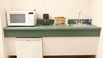 Uma cozinha compacta com micro-ondas, cafeteira e pia.