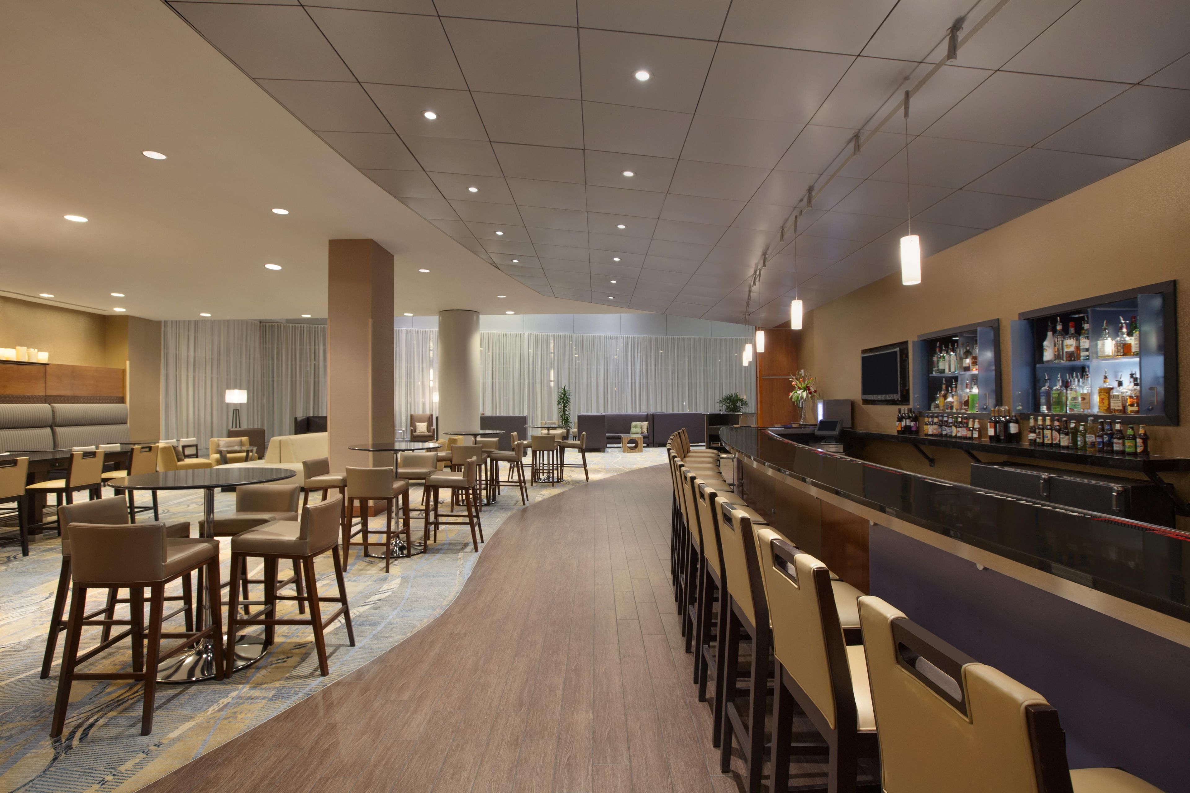 Um saguão de hotel com área de bar, sofás e balcão de recepção.