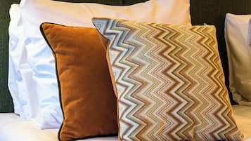 Uma cama com três almofadas: uma com padrão em zigue-zague, outra lisa e uma branca.