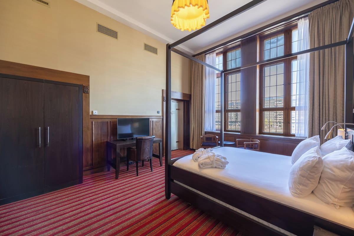 Quarto de hotel com uma cama grande, uma escrivaninha e um guarda-roupa.