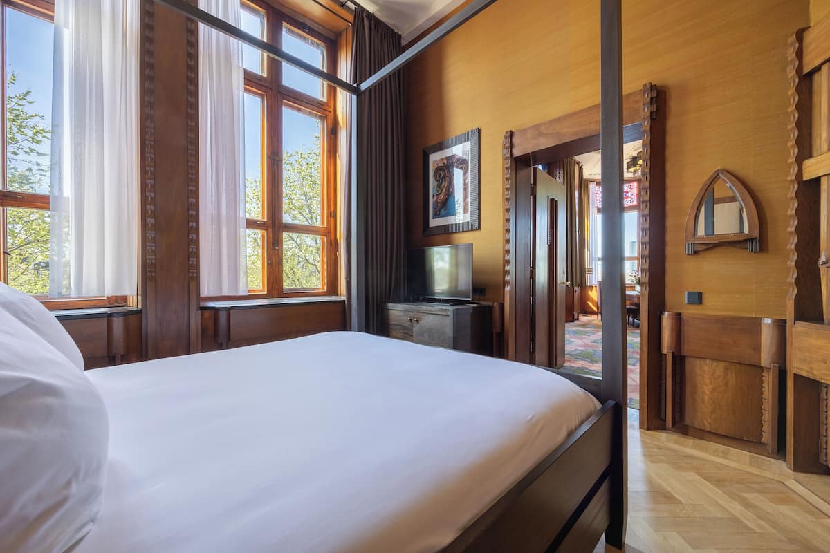 Quarto de hotel com uma cama grande, paredes de madeira, uma televisão e vista para o exterior.