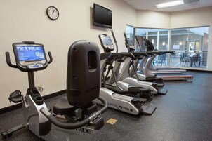 Centro de ginástica com esteiras, elípticos e bicicleta ergométrica, equipado com monitores de frequência cardíaca.