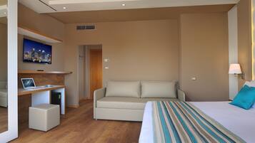 Quarto de hotel moderno com uma cama, um sofá, uma escrivaninha com um laptop, uma televisão e um pequeno armário.