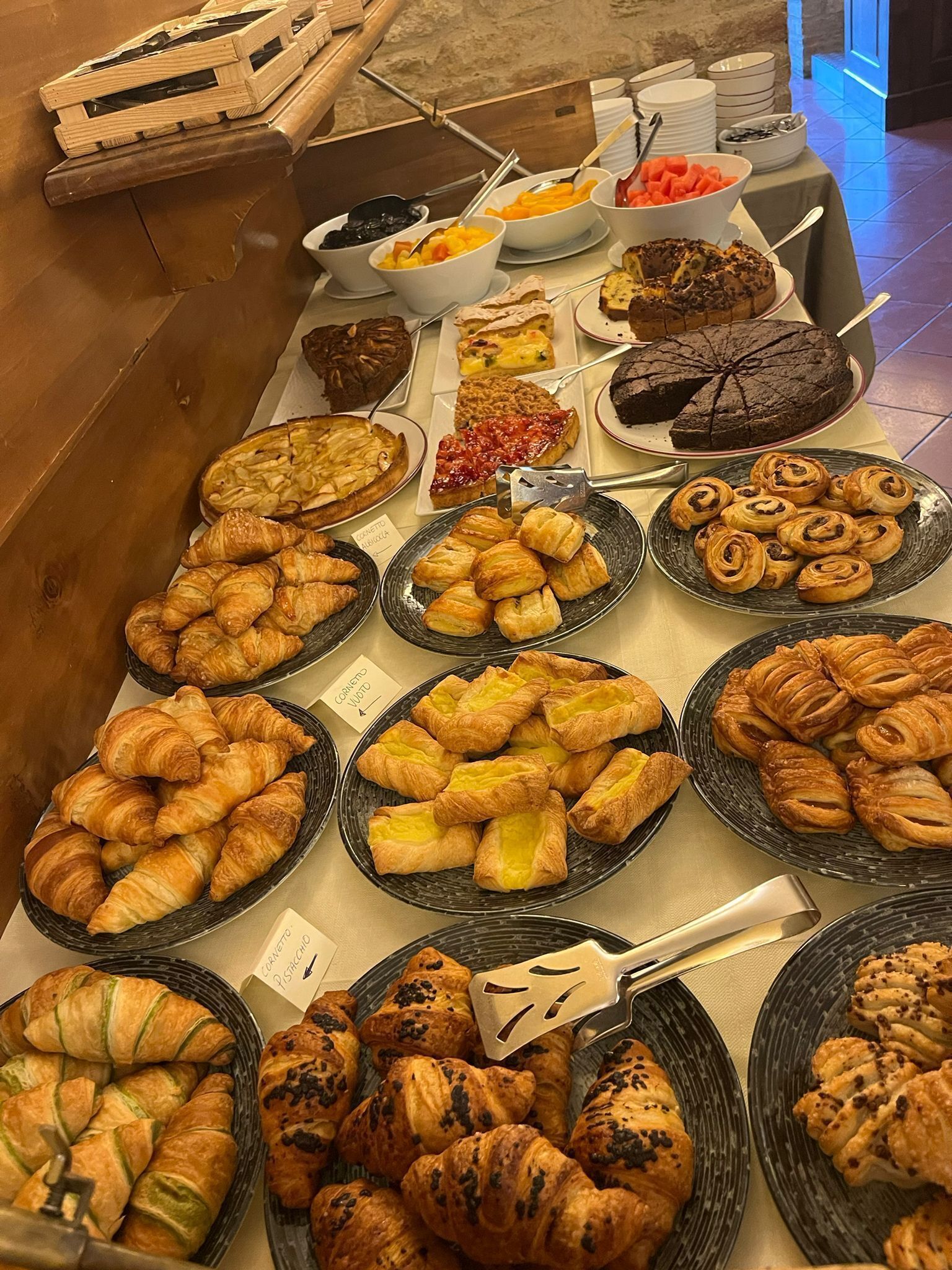 Buffet com diversos doces, incluindo croissants e bolos, dispostos em pratos e cestas.