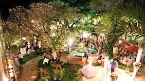Evento ao ar livre com palco circular, mesas e convidados.