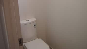 Uma casa de banho pequena e limpa, com sanita, janela e porta.