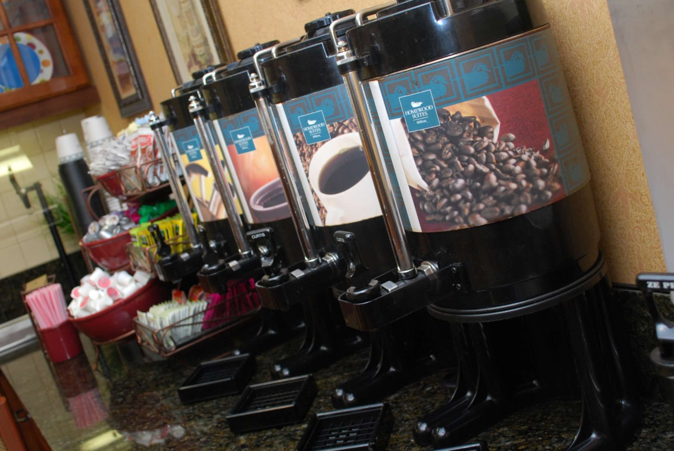Uma estação de café com vários dosadores identificados como "Homfood Suites".