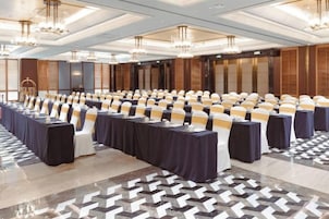 Uma sala de conferências com mesas, cadeiras em fileiras e um palco.