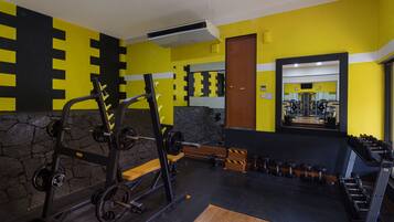 Uma academia com área de musculação, bancos e espelho.