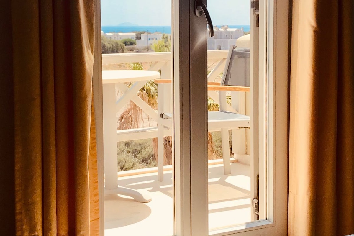 Quarto com porta de vidro deslizante que dá para uma varanda externa com vista para o mar.