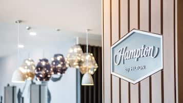 Placa de hotel com o nome 'Hampton by Hilton' e um quadro hexagonal.