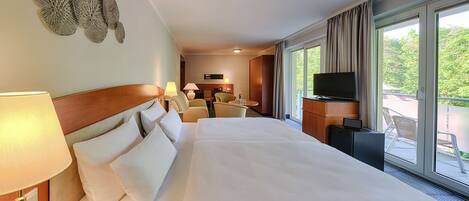 Quarto de hotel com cama grande, televisão, escrivaninha e varanda com vista.