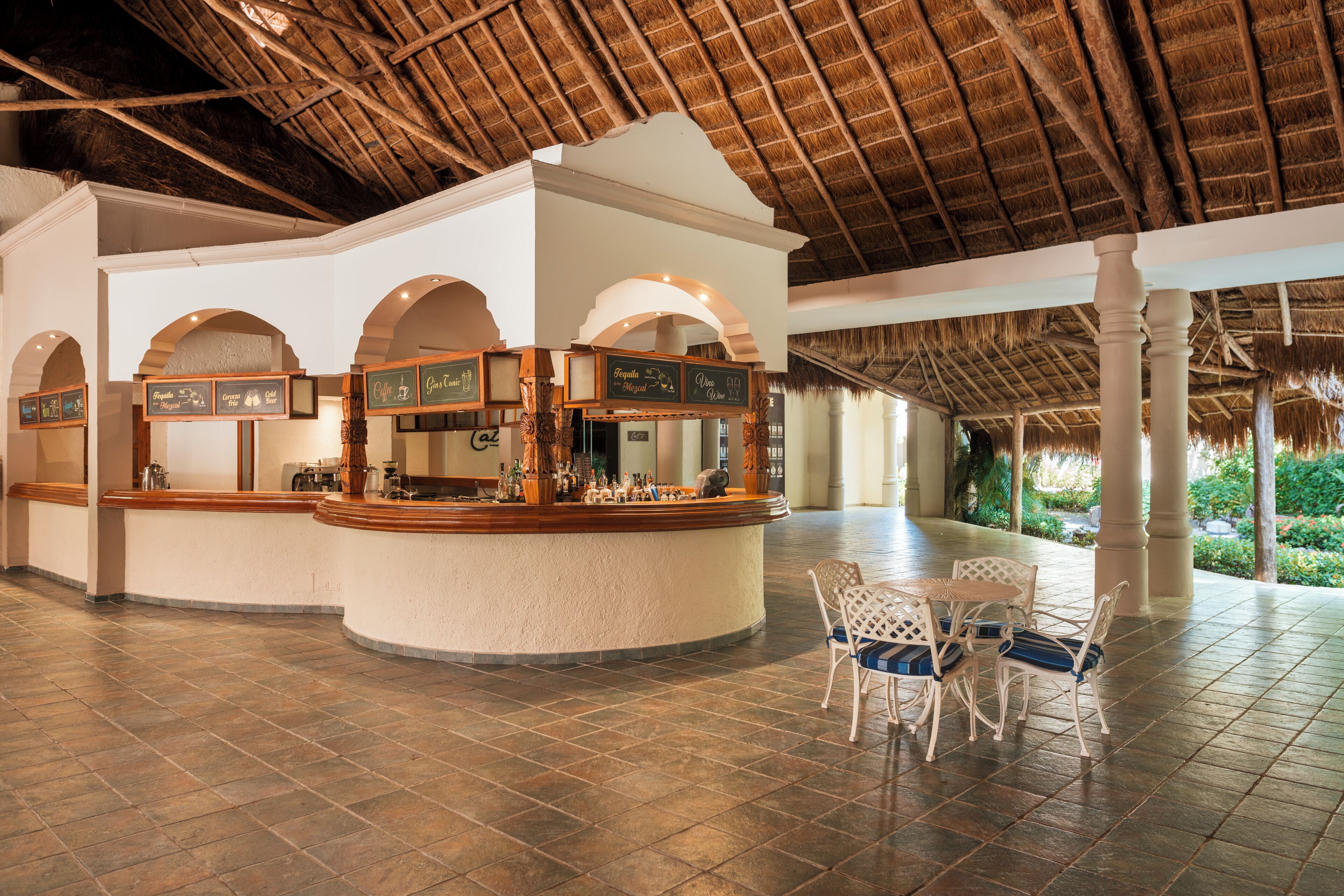 Um hall amplo com área de bar, assentos e teto de palha.