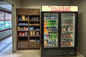 Máquina de vendas com lanches e bebidas, e uma estante com diversos produtos embalados.