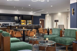 Um saguão de hotel com áreas de estar, um bar e uma mesa de recepção.