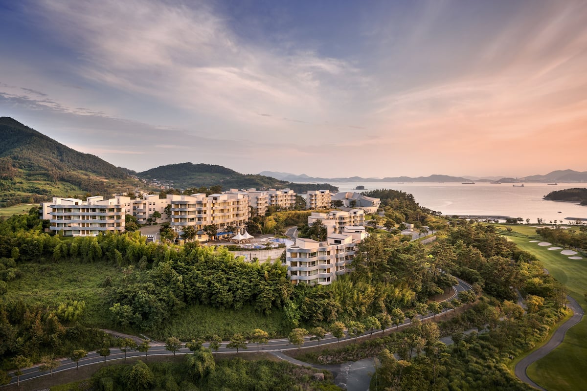 Zona residencial com edifícios de apartamentos modernos, um campo de golfe e um corpo de água ao fundo.