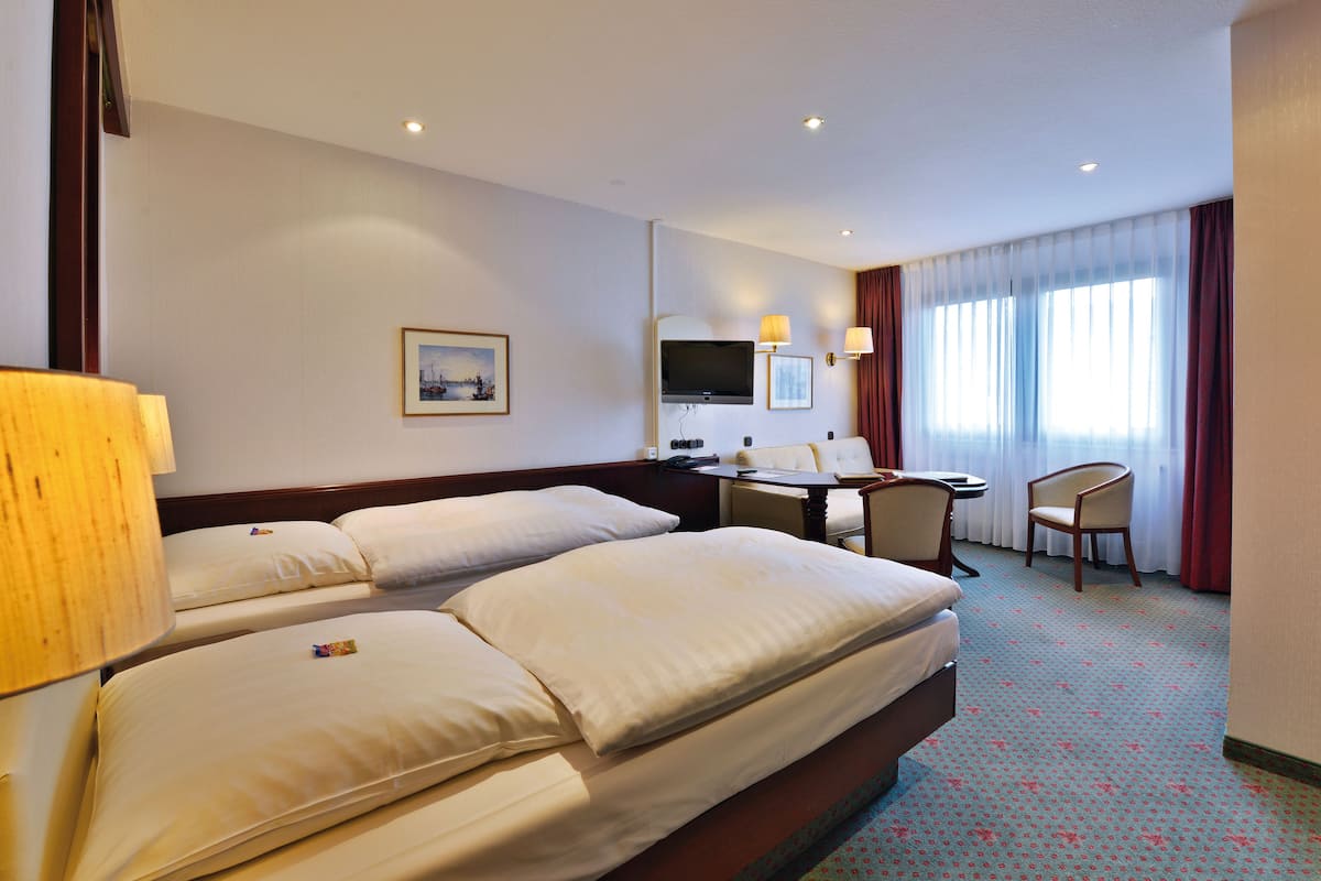 Quarto de hotel com duas camas, uma mesa com televisão e uma cadeira.