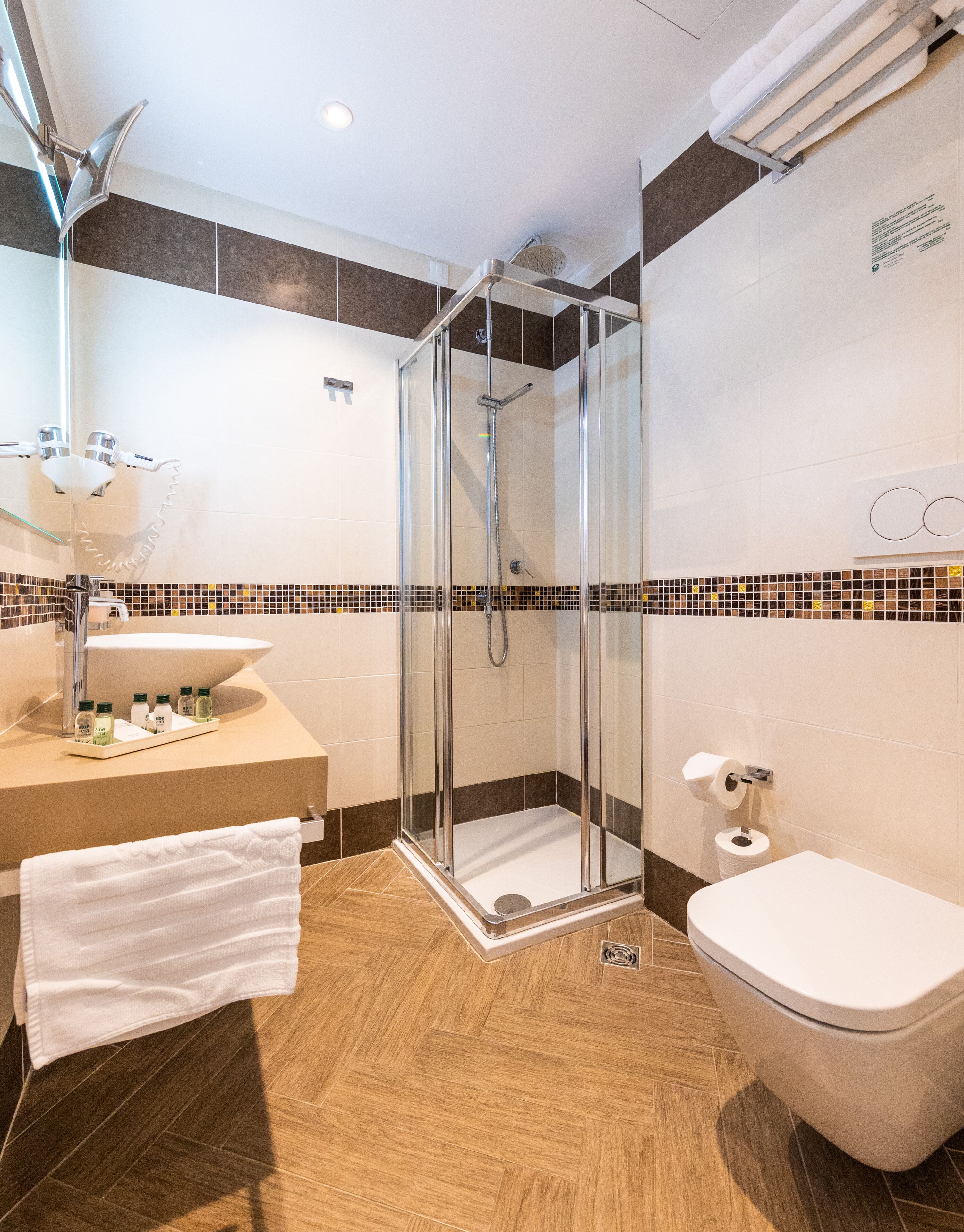 Uma casa de banho moderna com chuveiro em cabine de vidro, pia com artigos de higiene e sanita.