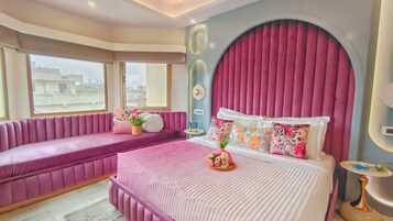 Quarto com uma cama grande, um banco embutido e uma janela com vista para a cidade.