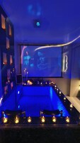 Quarto com uma grande tela, piscina e velas.