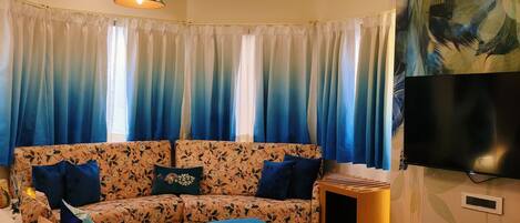 Quarto com duas camas, um ventilador de teto, uma TV e um quadro na parede.