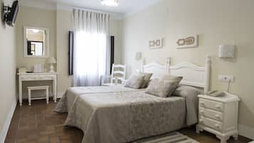 Quarto com cama de casal, mesa de cabeceira, escrivaninha, cadeira, espelho e janela com cortinas.