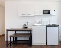 Uma cozinha compacta com micro-ondas, cafeteira e lava-louças.