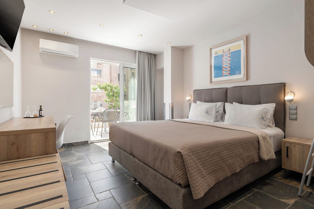 Quarto de hotel moderno com uma cama grande, uma escrivaninha e vista para a cidade.