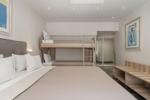 Quarto de hotel moderno com beliche, sofá-cama e um banco de madeira ao longo da parede.