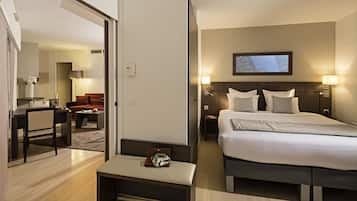 Quarto de hotel moderno com uma cama grande, mesas de cabeceira, escrivaninha e uma cadeira.